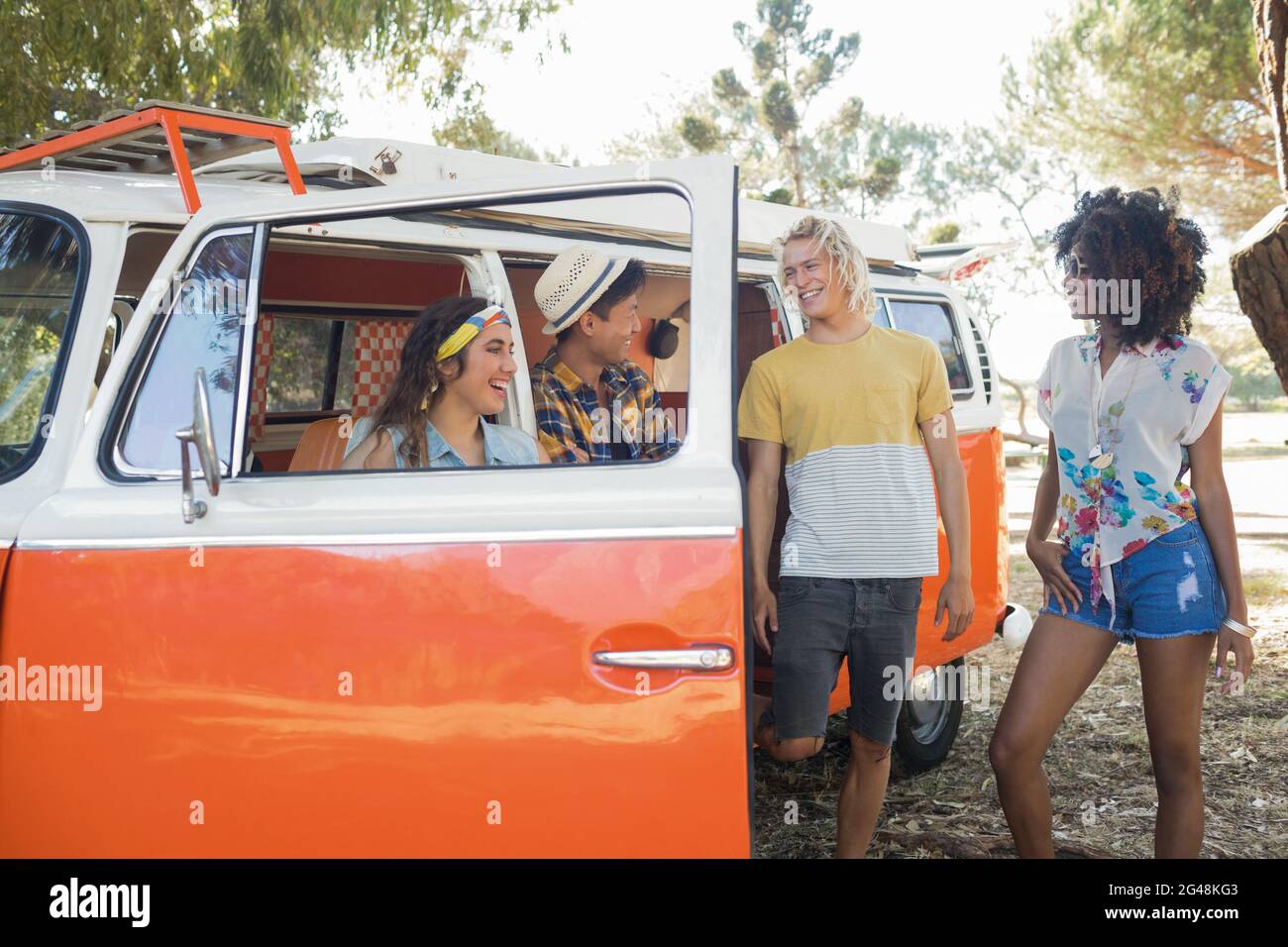 Smiling friends standing by camper van at campsite Stock Photo - Alamy