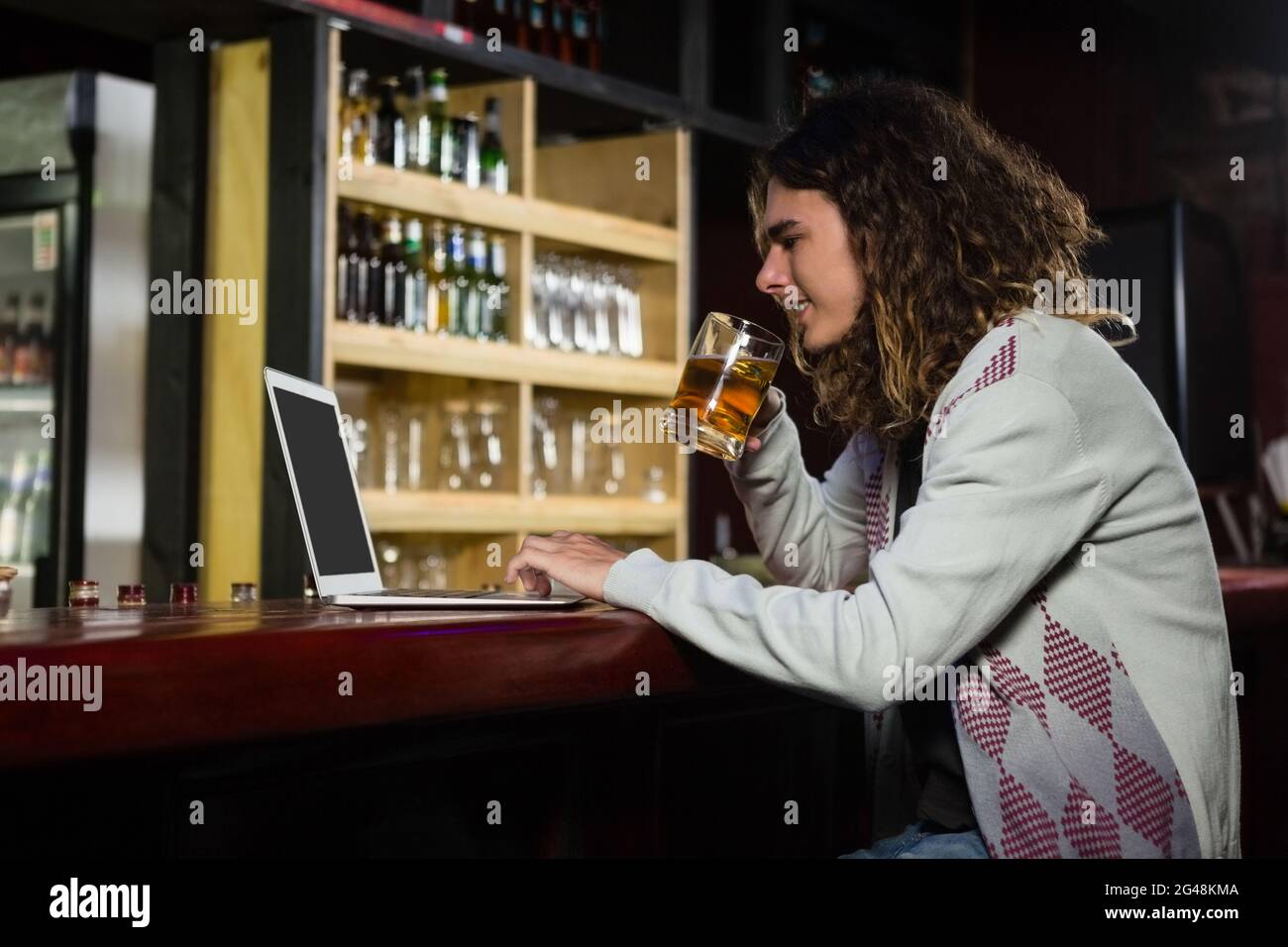 Man having beer while using laptop at counter Stock Photo - Alamy
