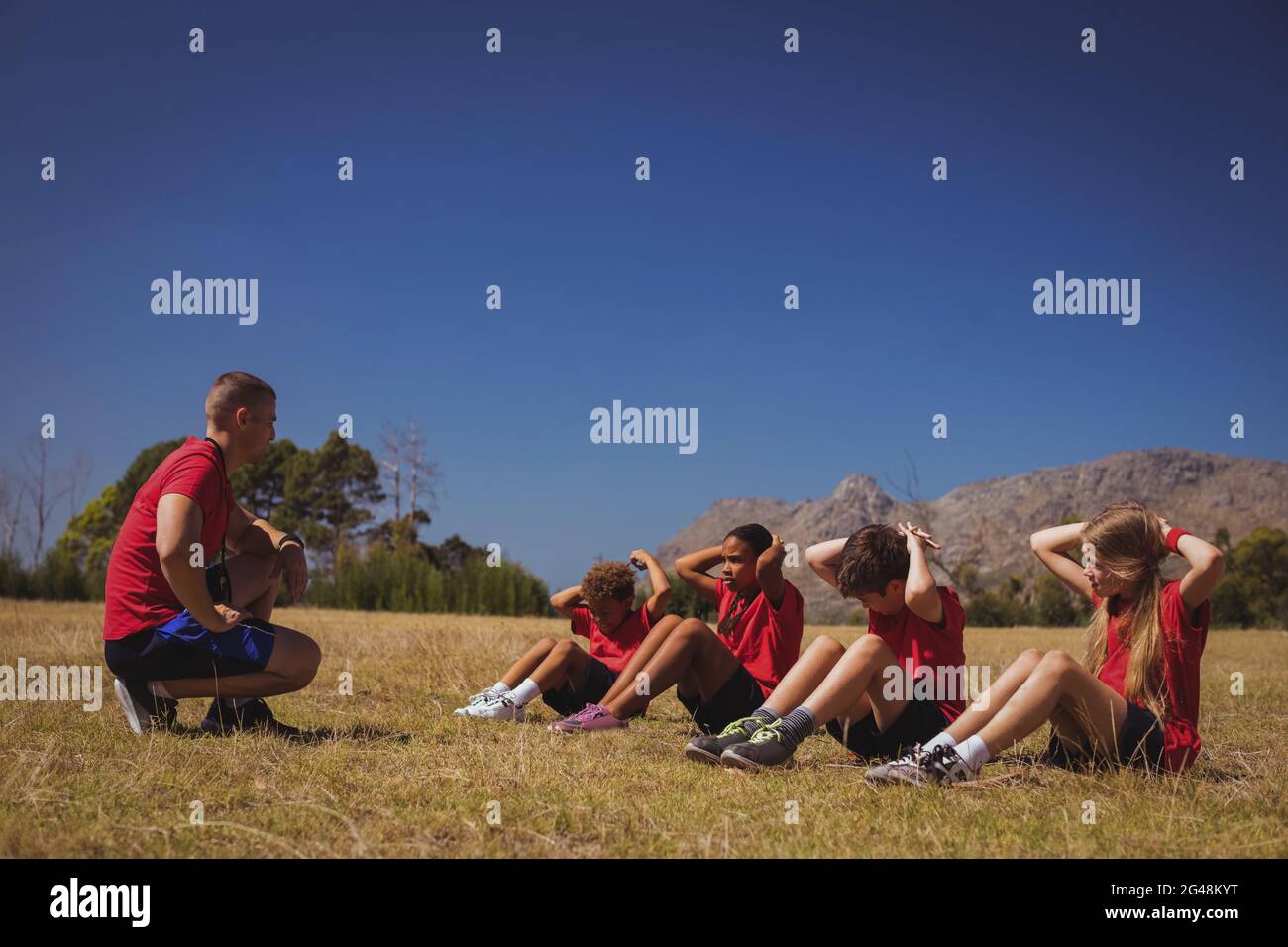 Trainer instructing kids while exercising in the boot camp Stock Photo ...