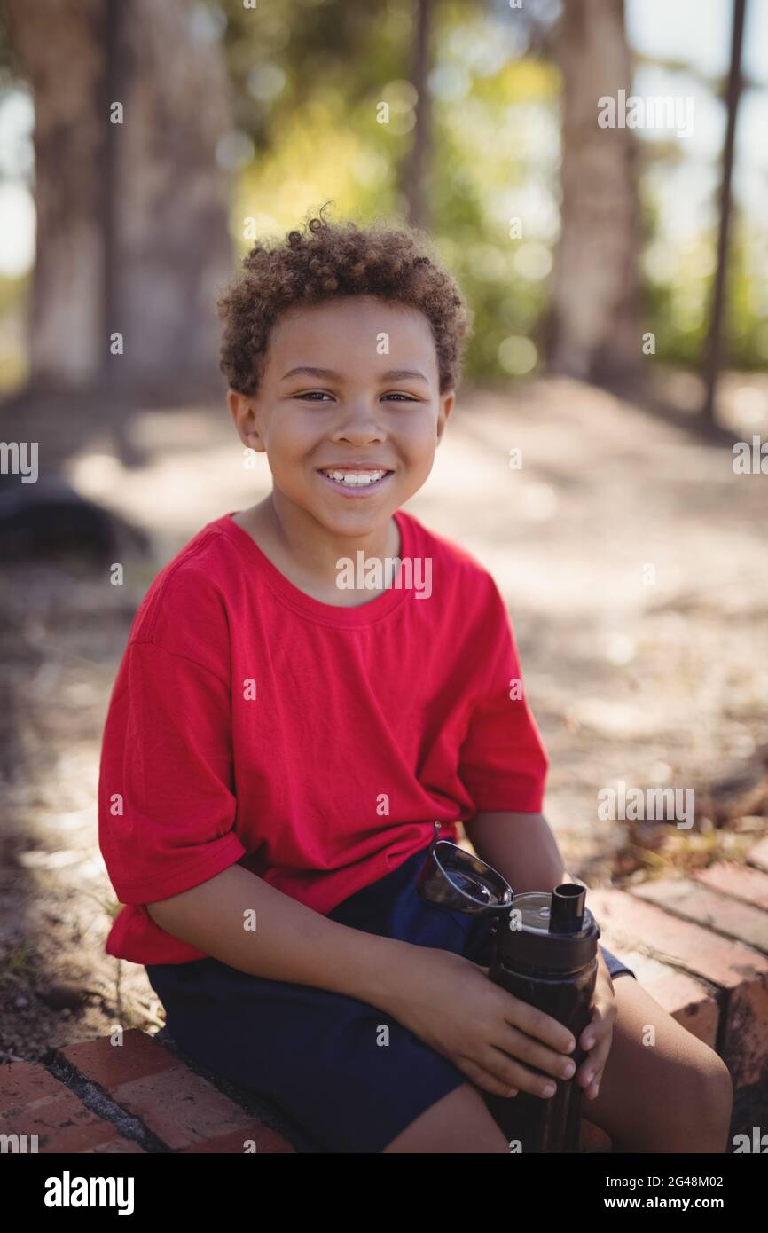 Portrait of smiling boy relaxing after workout during obstacle course ...