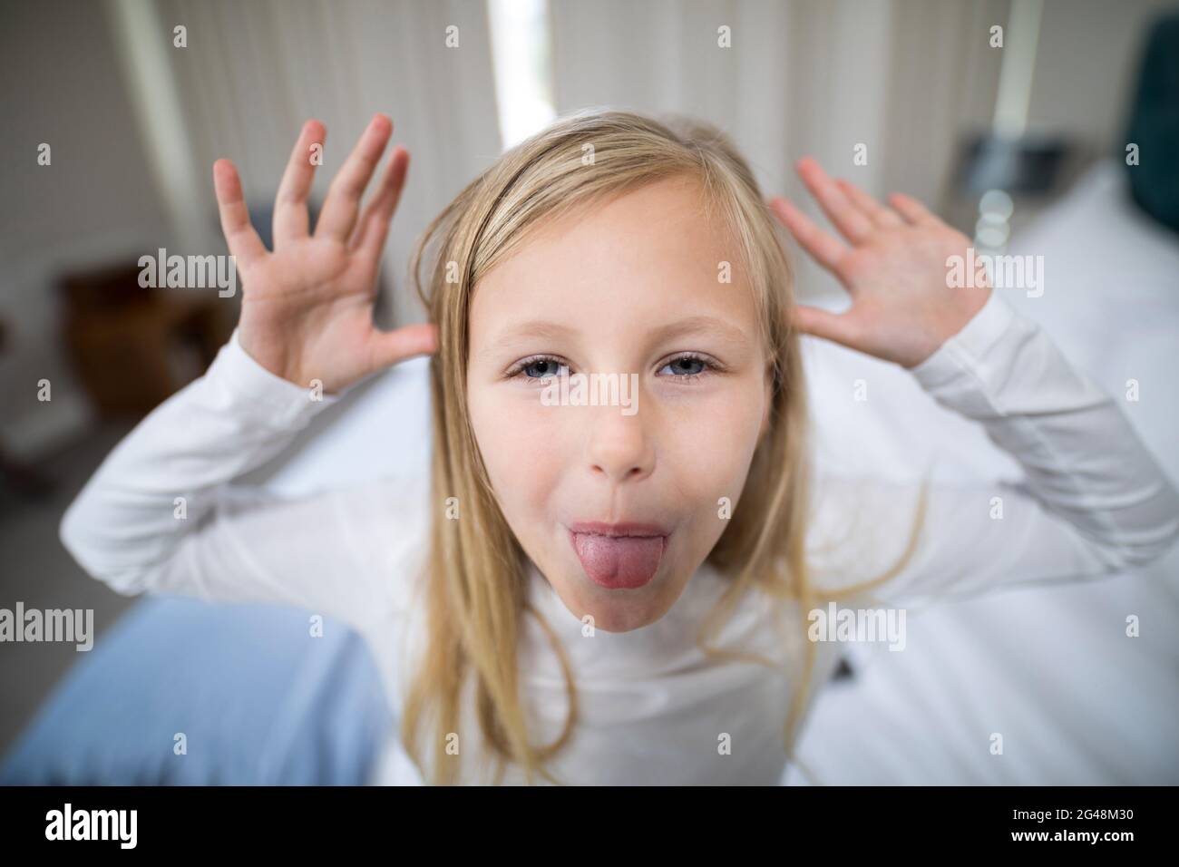 Portrait of girl making facial expression in bedroom Stock Photo - Alamy