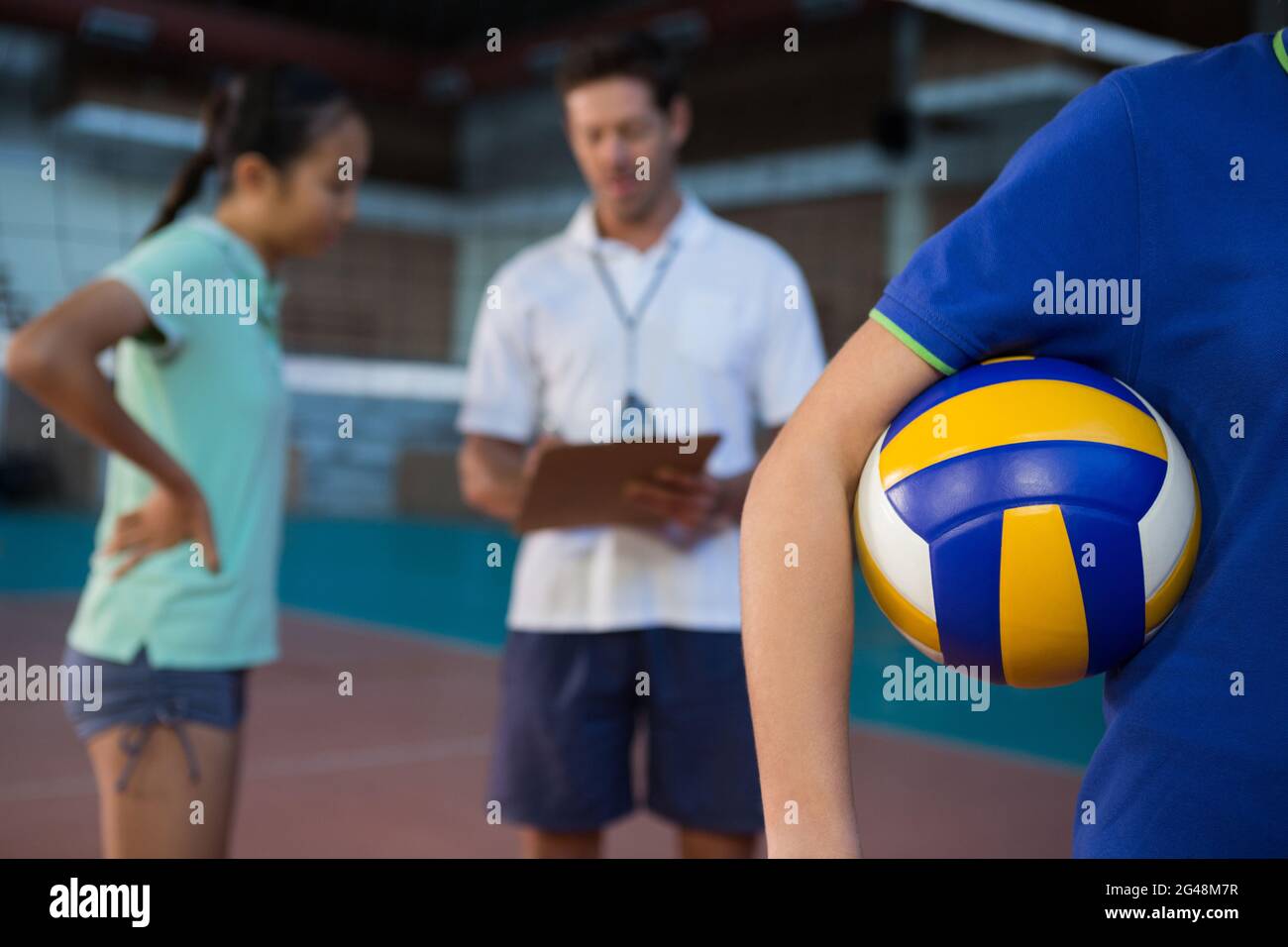 Volleyball player holding ball in court Stock Photo - Alamy