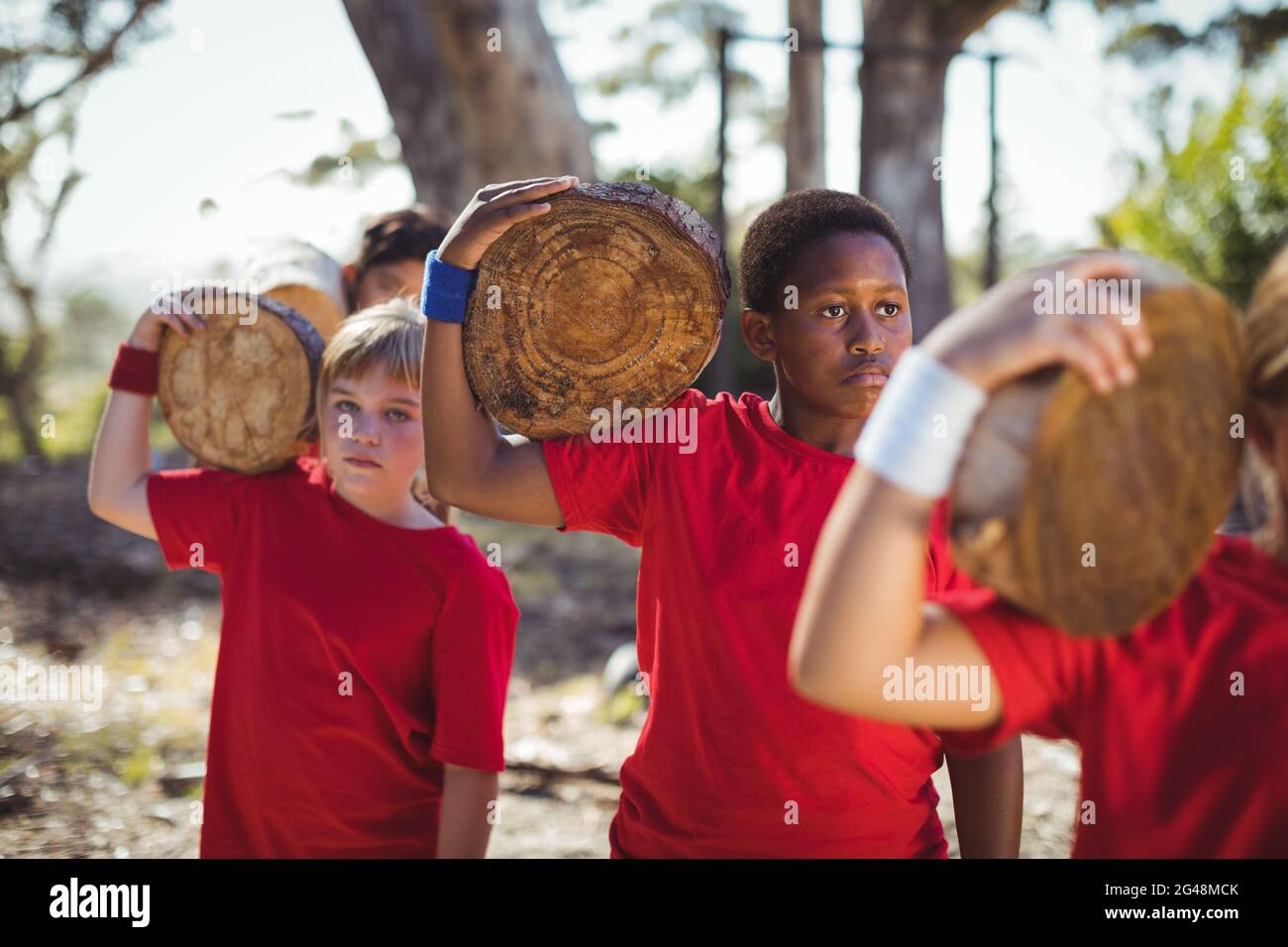 Kids carrying wooden log during obstacle course training Stock Photo ...
