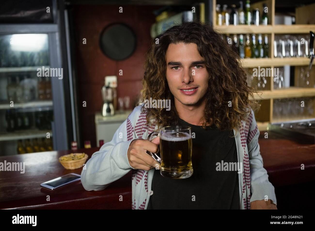 Man having beer while leaning against bar counter Stock Photo - Alamy