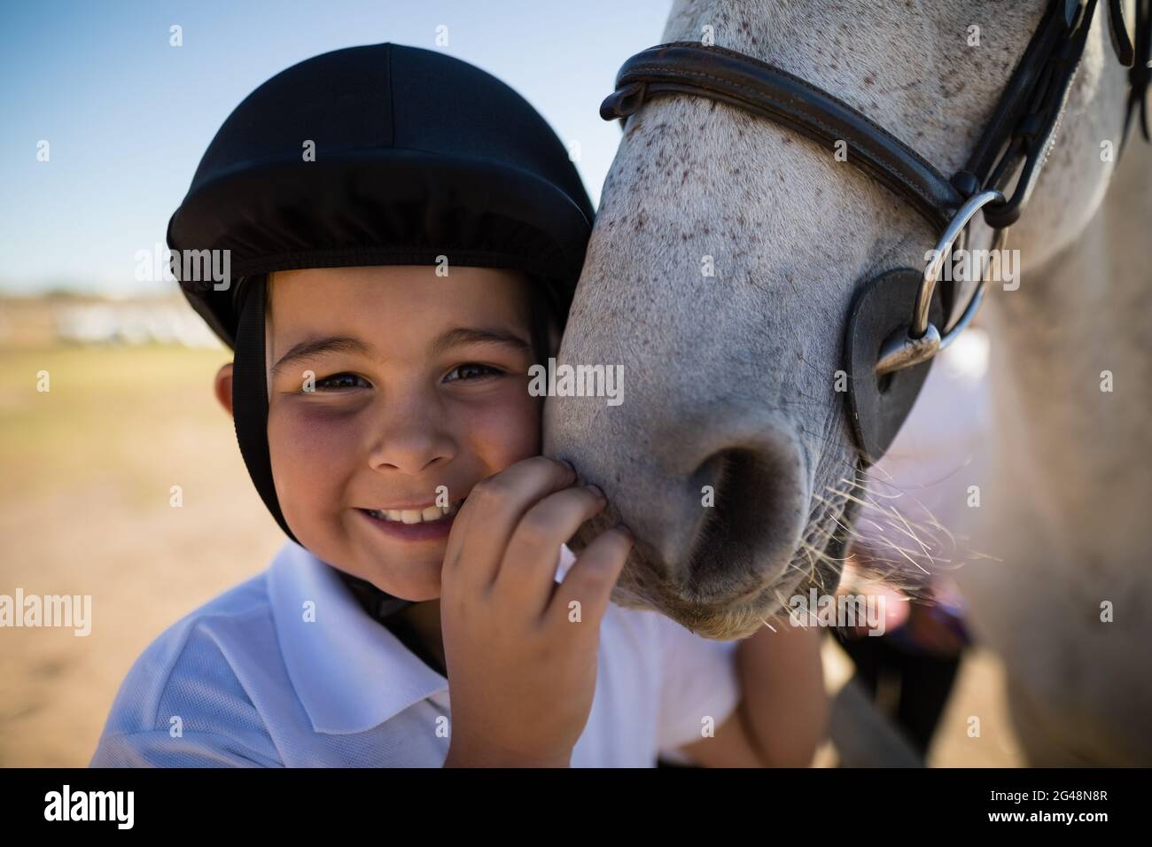 Smiling rider boy touching the white horse Stock Photo - Alamy