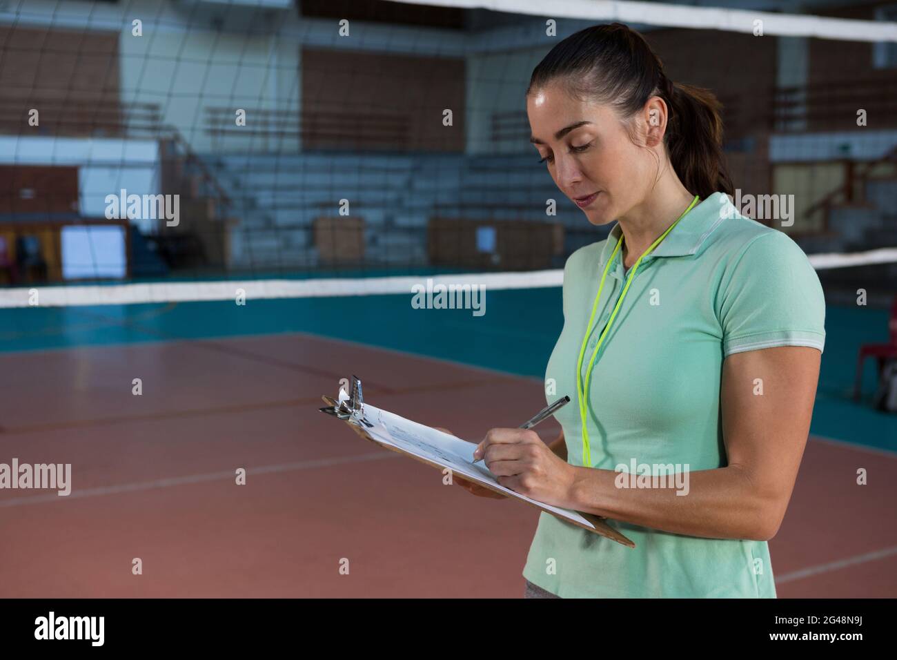 Female volleyball coach writing on clipboard Stock Photo - Alamy