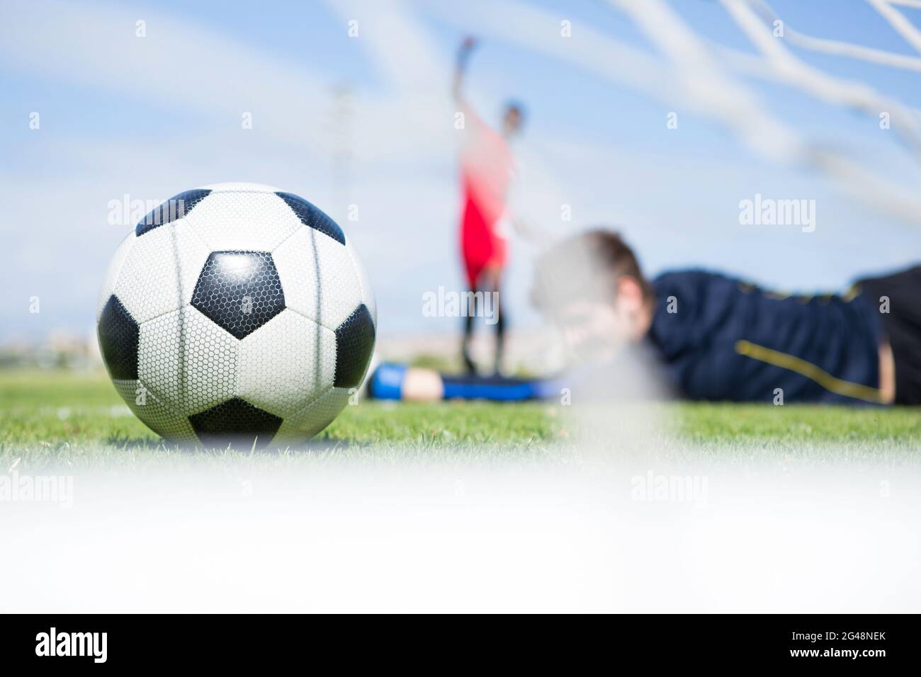 Goalkeeper lying on field while playing soccer Stock Photo - Alamy