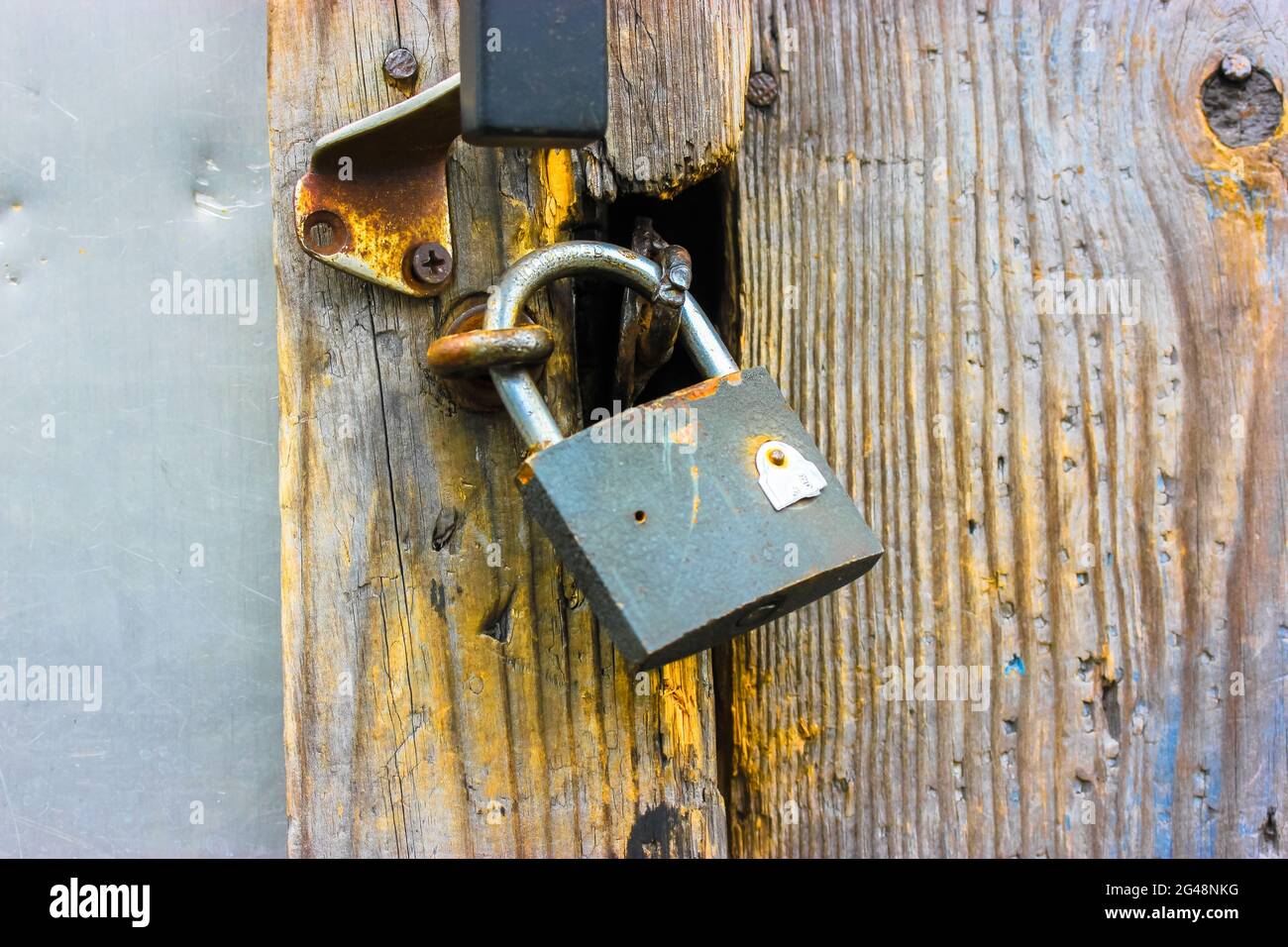 Old lock hanging on a wooden wall or brown door close-up. A rusty ...