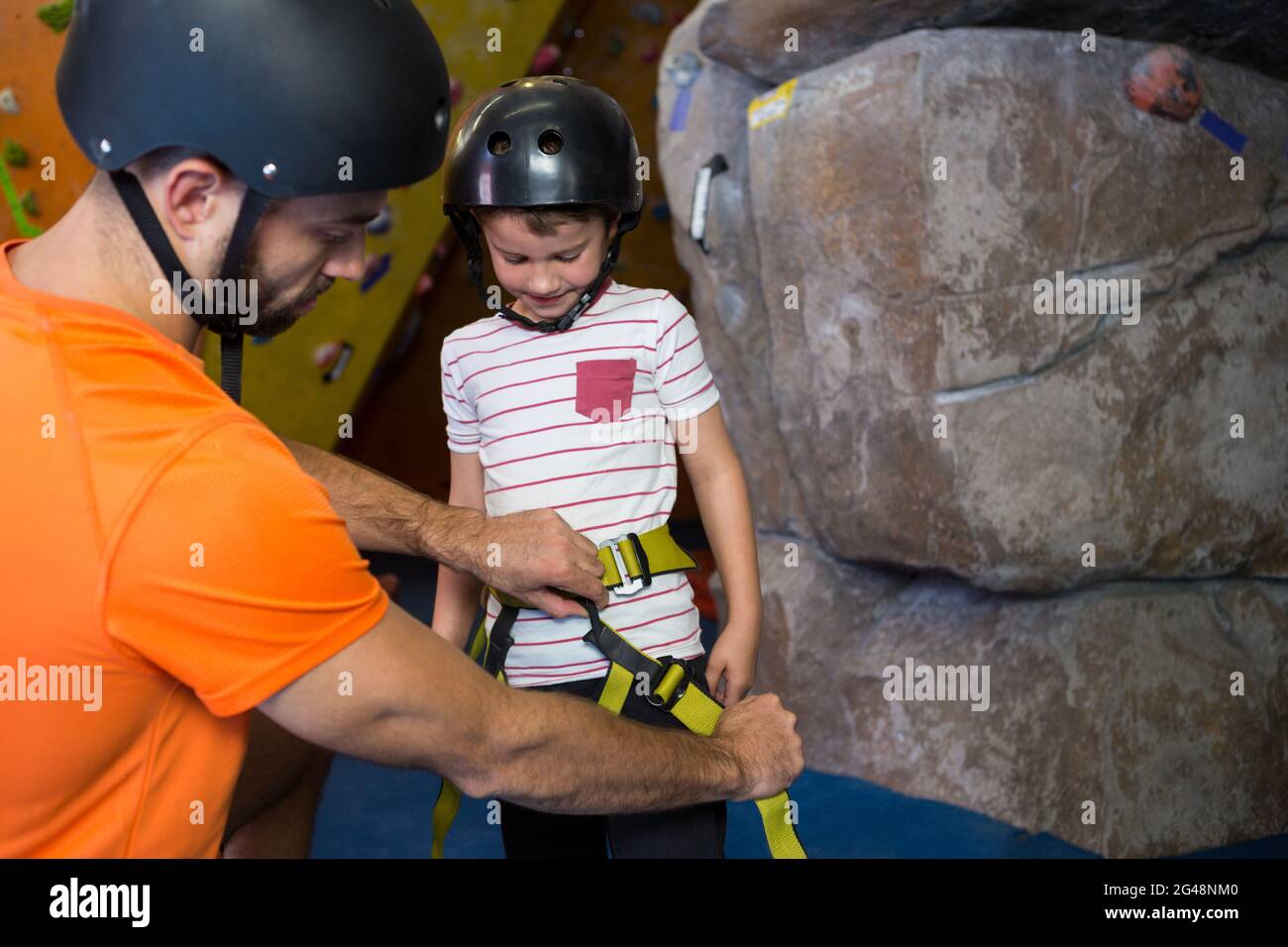 Trainer assisting boy to wear safety harness Stock Photo - Alamy