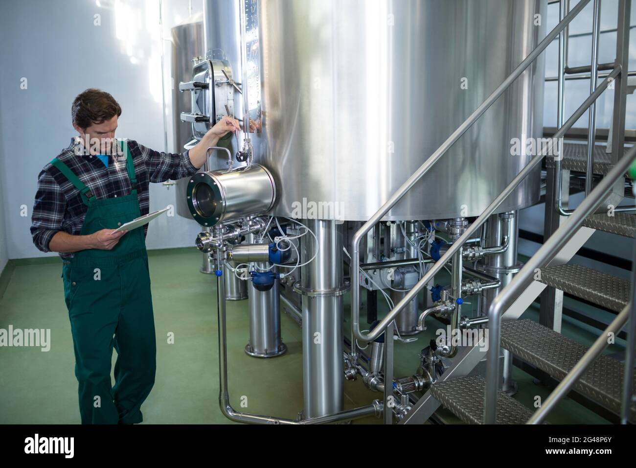 Male worker examining storage tank Stock Photo - Alamy