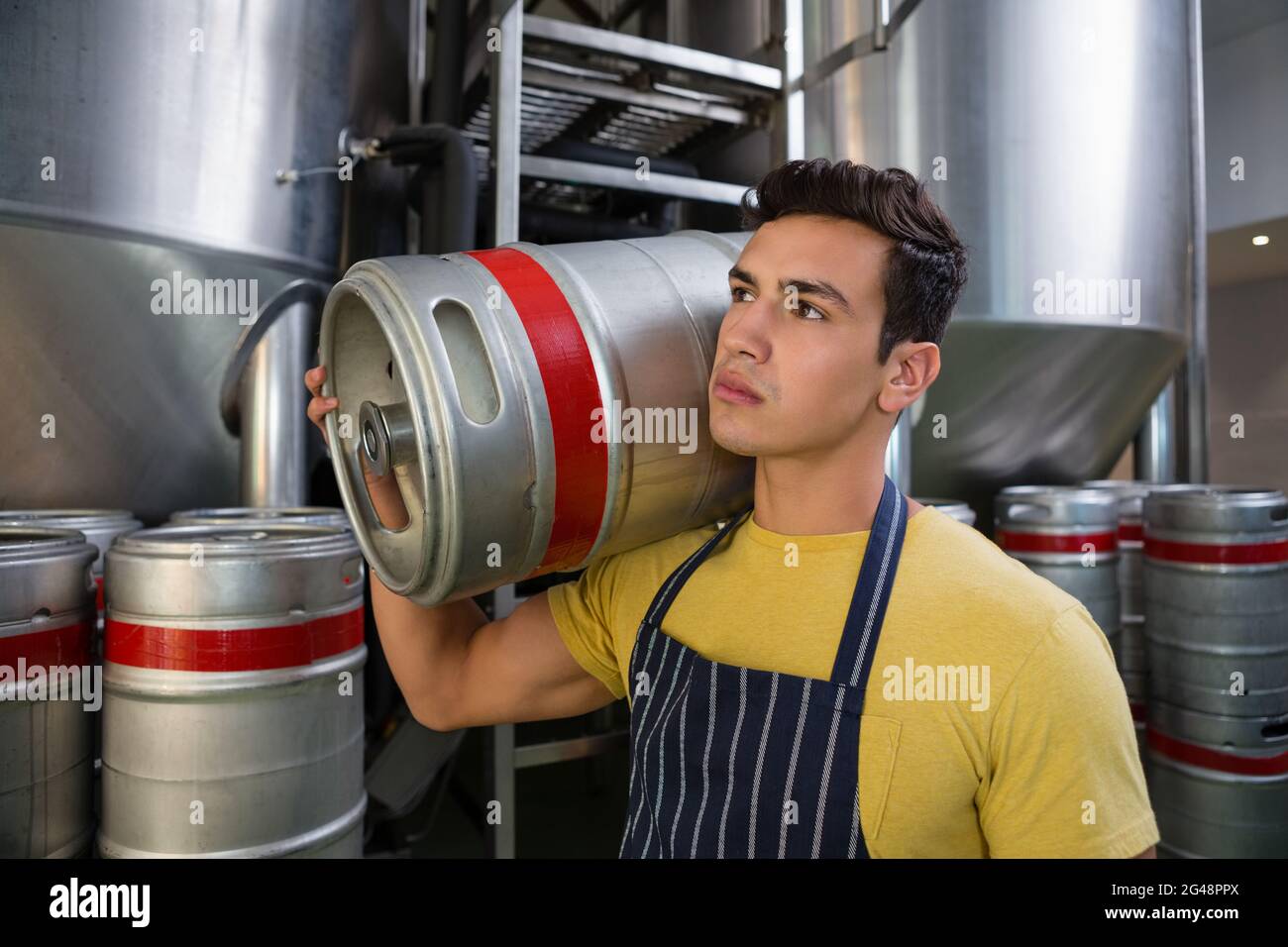 Worker looking away while carrying keg Stock Photo - Alamy