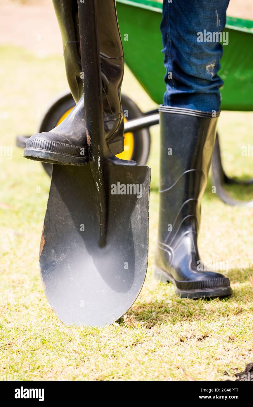 Low section of man in rubber boot with shovel Stock Photo - Alamy