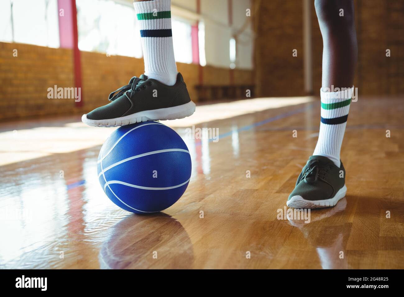 Low section of teenage boy stepping on basketball Stock Photo - Alamy