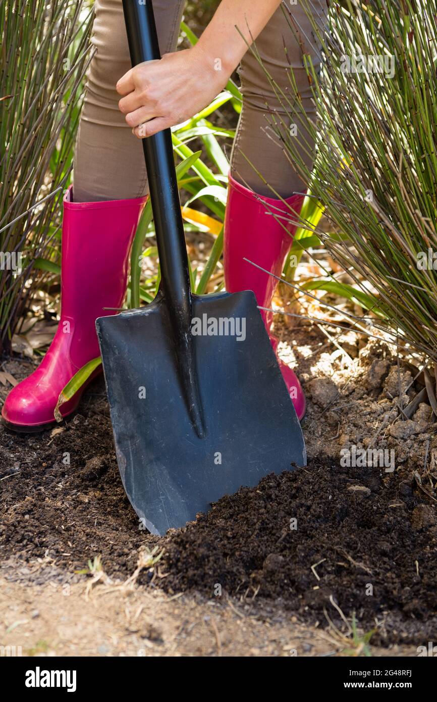 Low section of woman digging soil with shovel in garden Stock Photo - Alamy