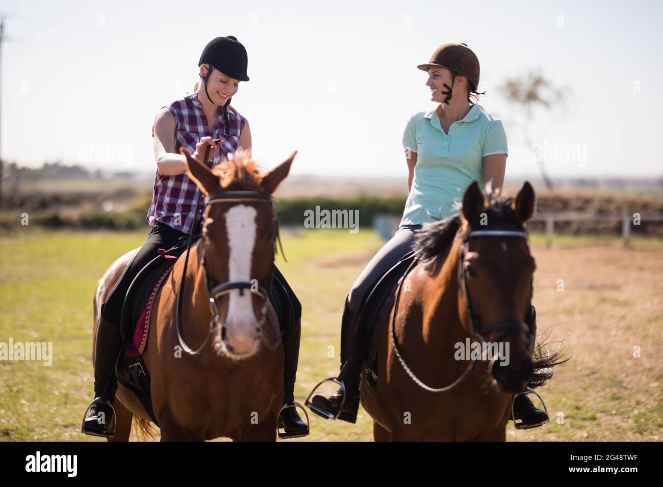 Full length happy female friends talking while horseback riding Stock ...