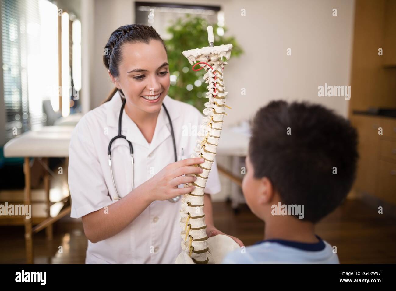 Smiling young female therapist explaining boy about spine Stock Photo ...