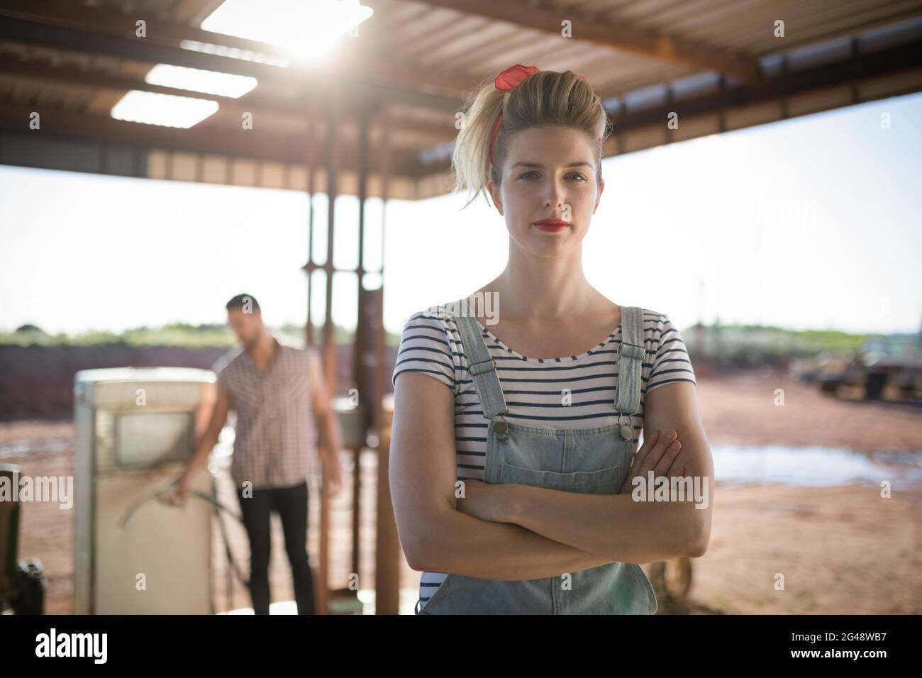 Woman standing with arms crossed at petrol pump station Stock Photo - Alamy