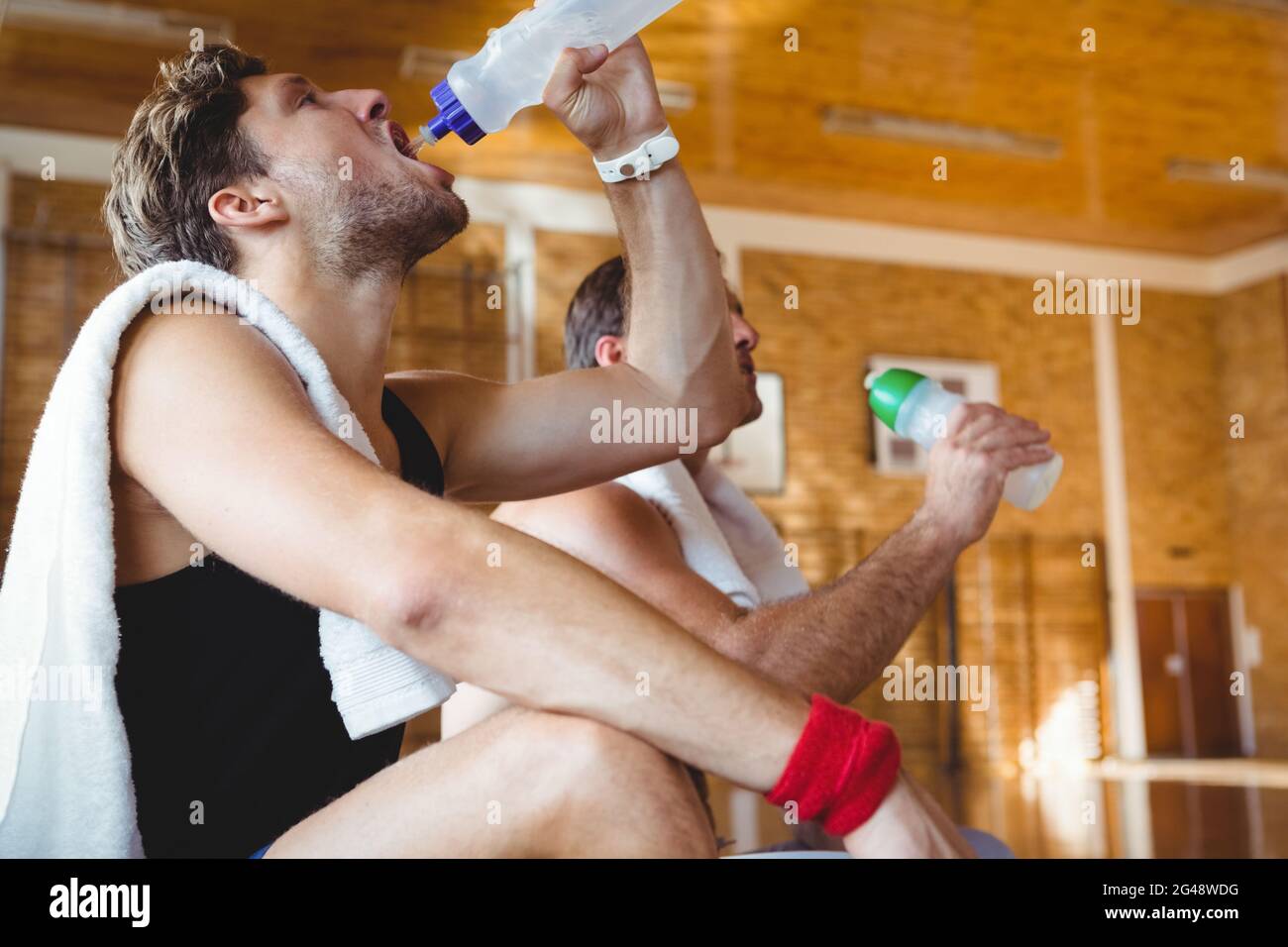 Male friends drinking water in court Stock Photo - Alamy