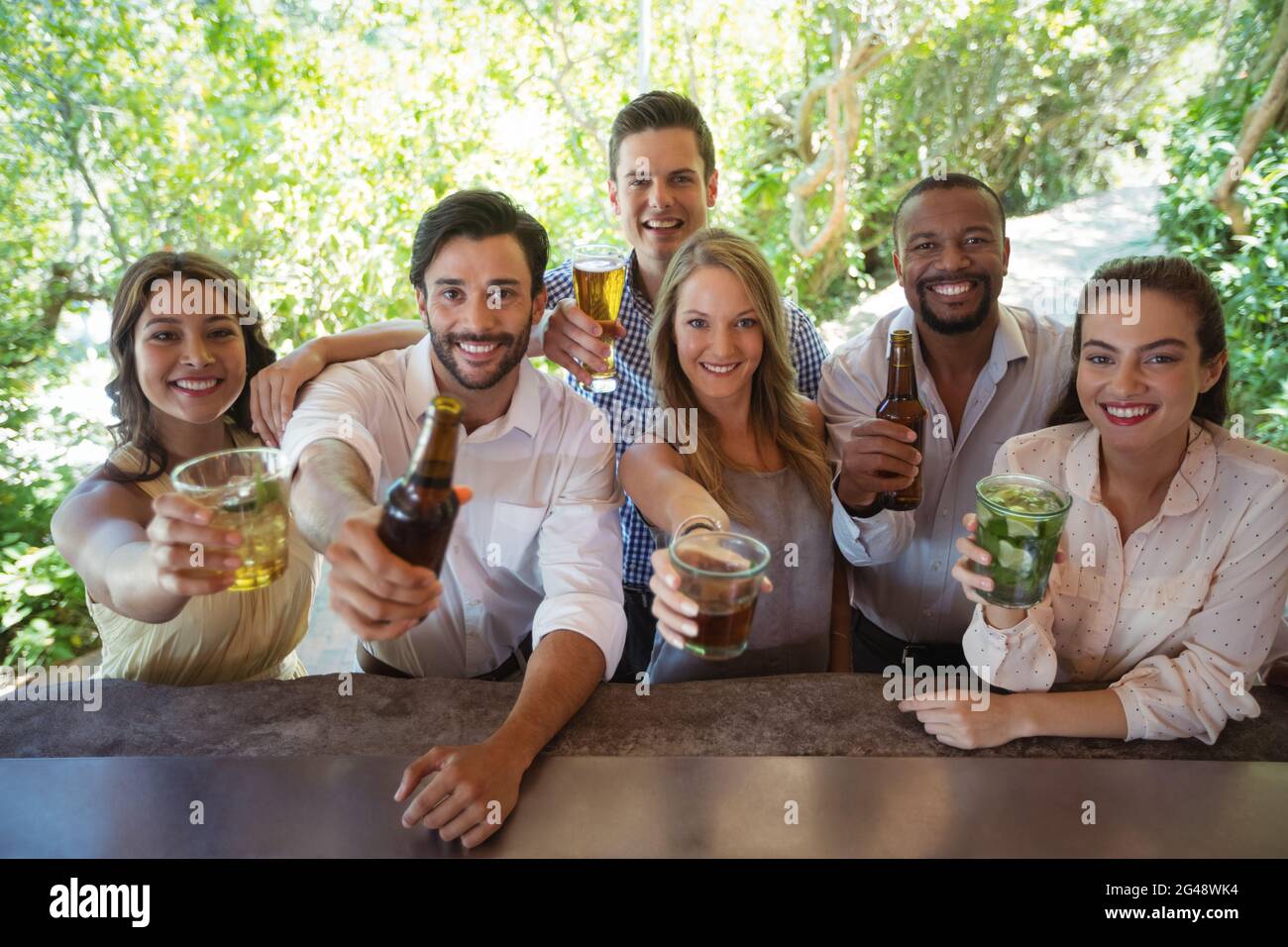 Portrait of smiling friends showing alcohol at counter Stock Photo - Alamy