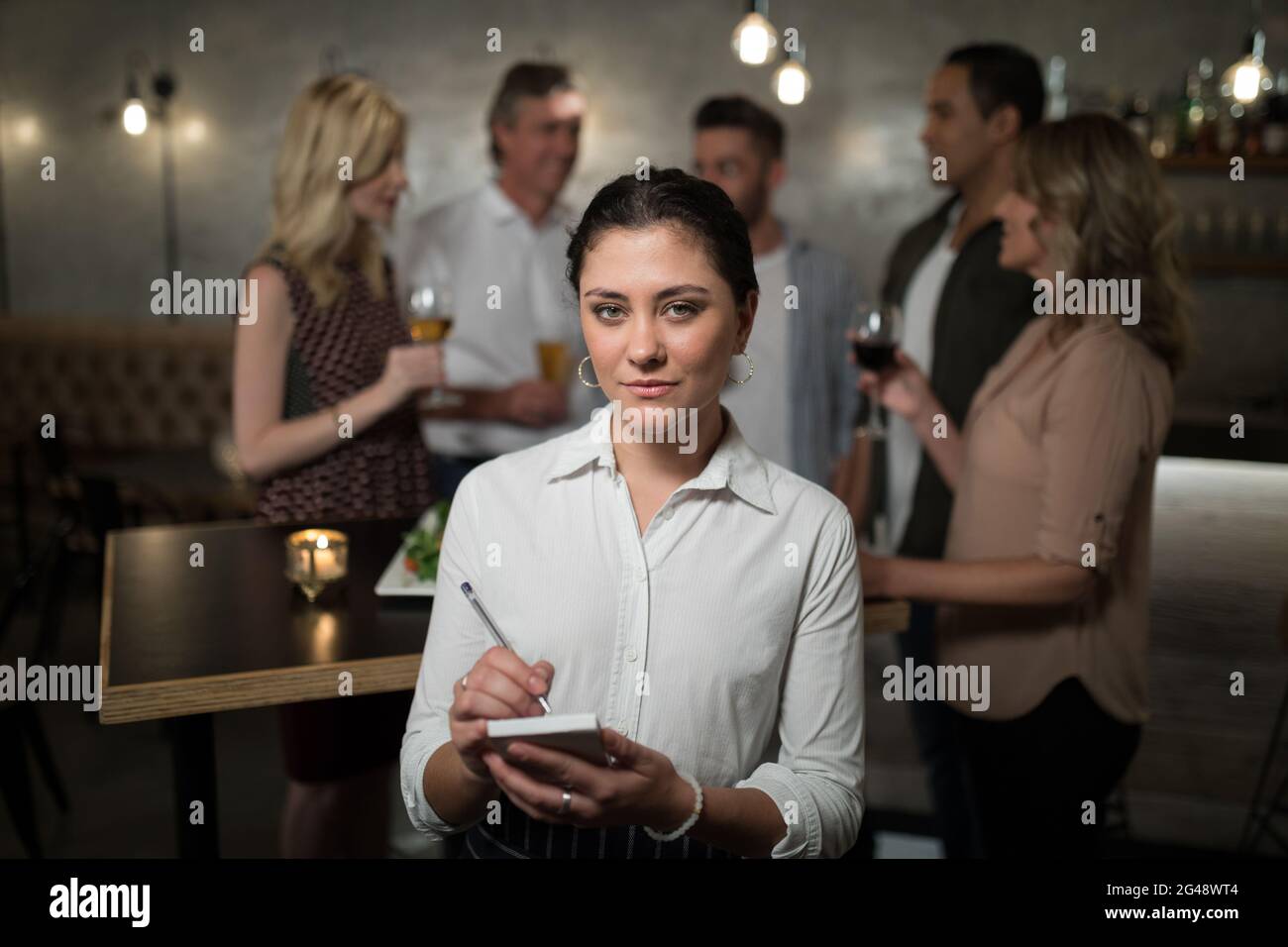 Beautiful waitress writing order in notepad Stock Photo - Alamy
