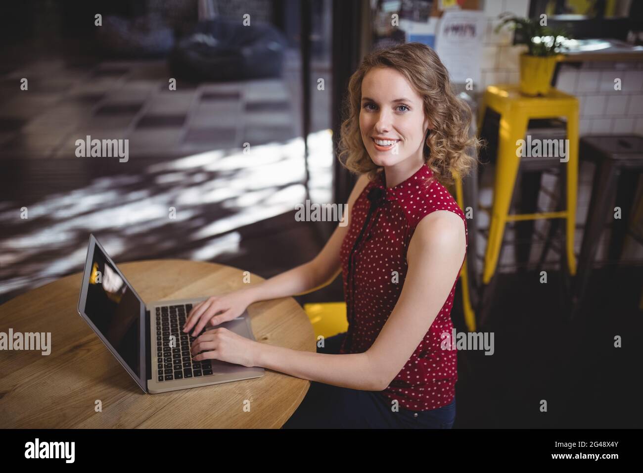 Portrait of beautiful young female customer sitting with laptop at ...