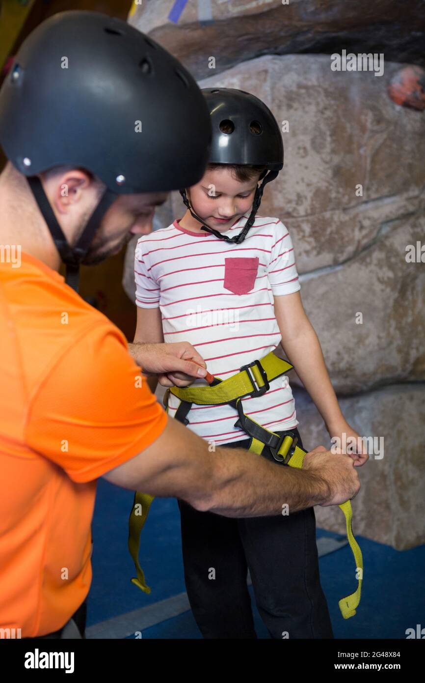 Trainer assisting boy to wear safety harness Stock Photo - Alamy