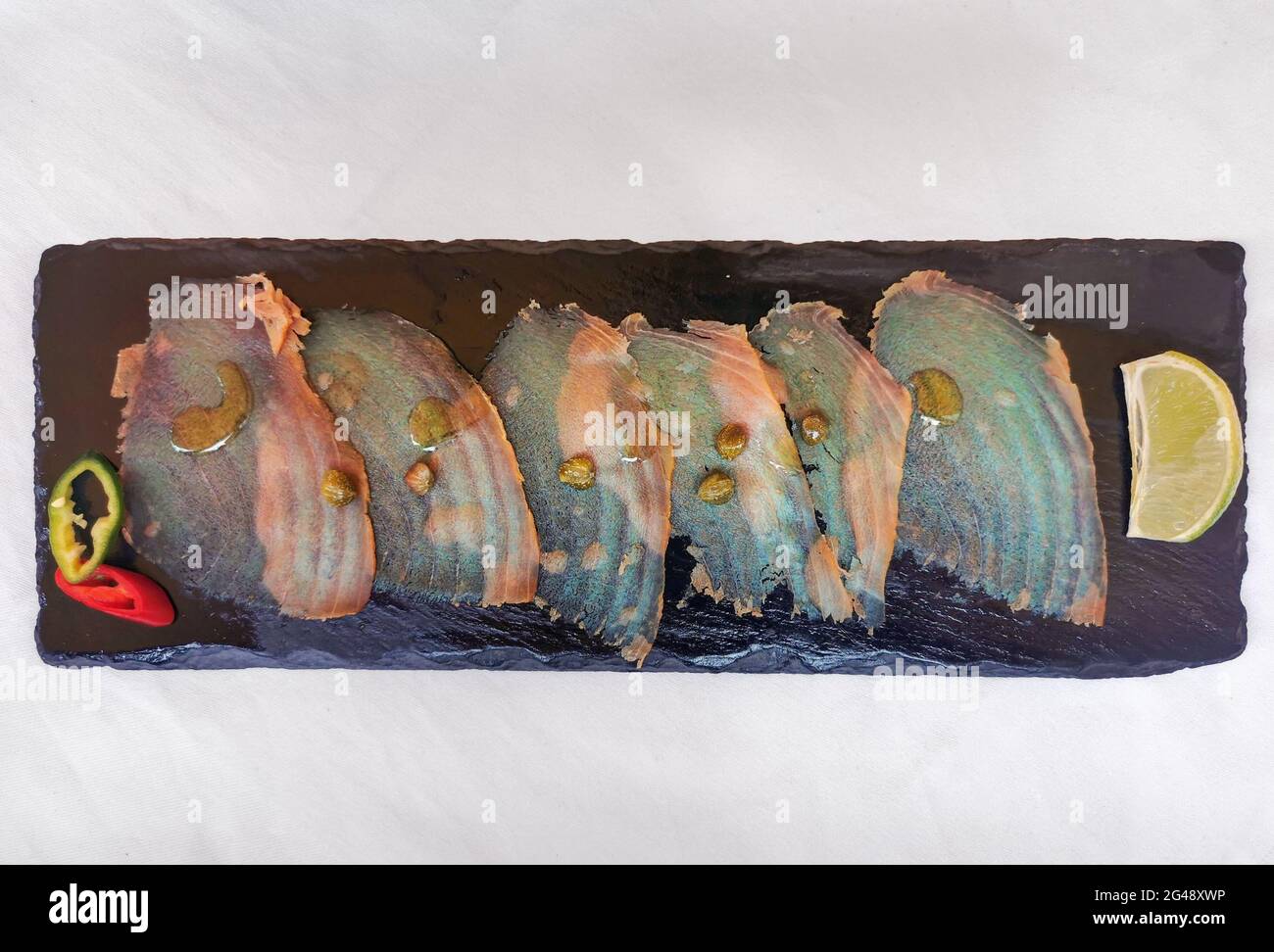 Top view of slices of smoked tuna served on rectangular black plate in ...