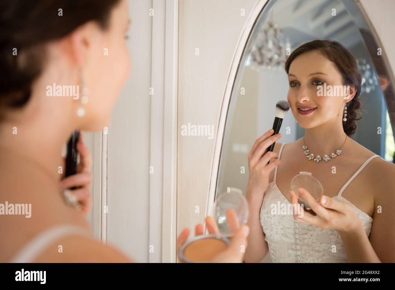 Side view of beautiful bride applying makeup reflecting on mirror Stock ...