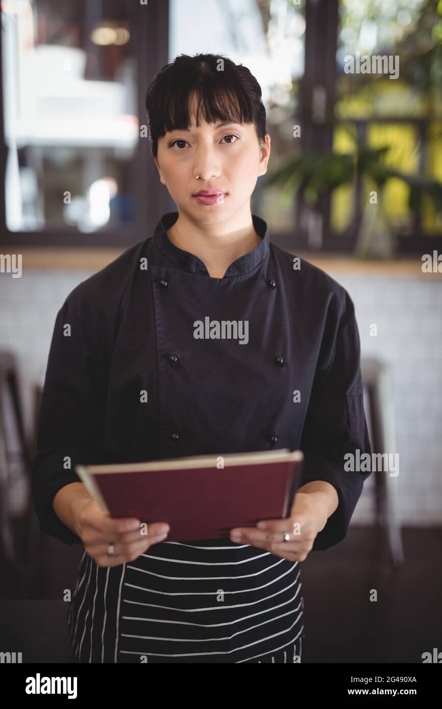Portrait of confident young waitress holding menu Stock Photo - Alamy
