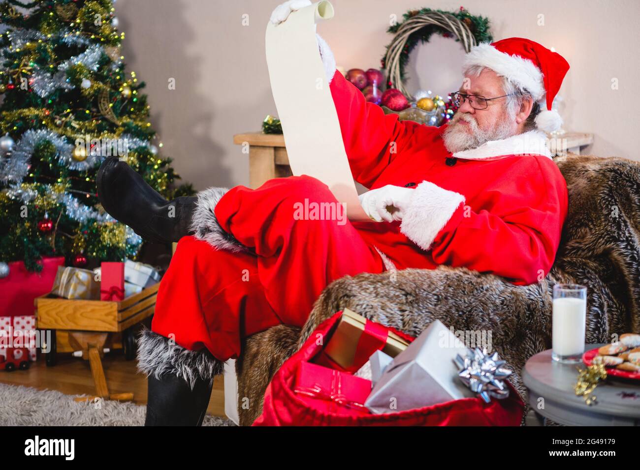 Santa Claus reading scroll in living room Stock Photo - Alamy