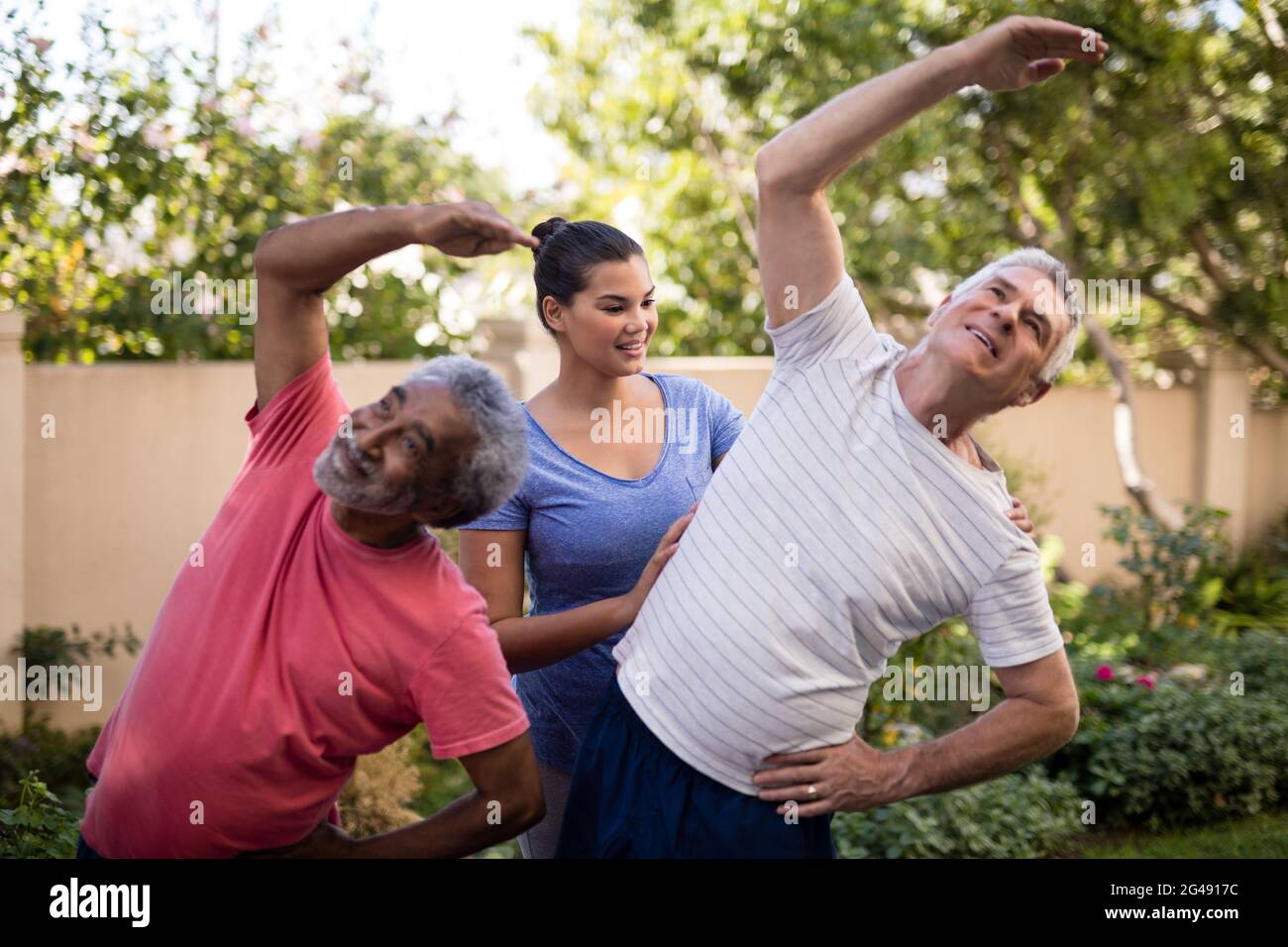 Smiling trainer guiding senior men during exercise Stock Photo - Alamy