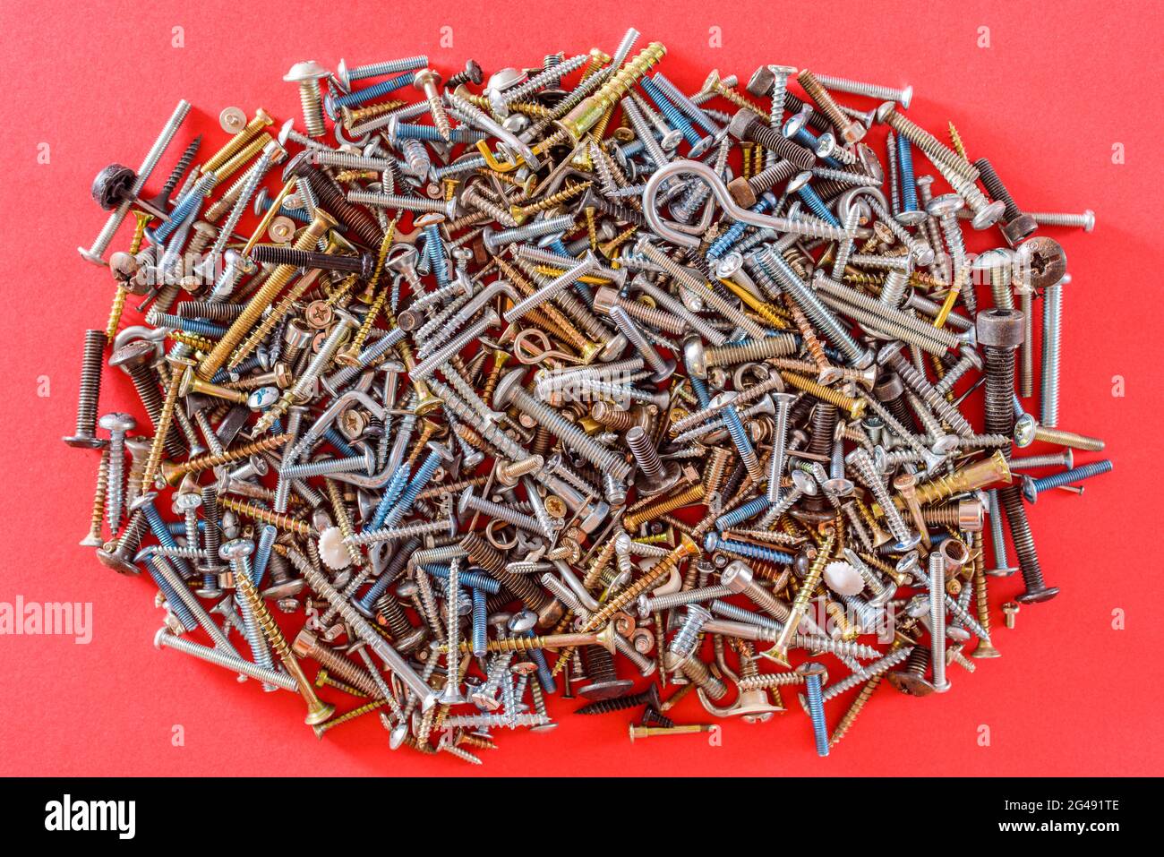 Isolated pile of screws of different types on red color background ...