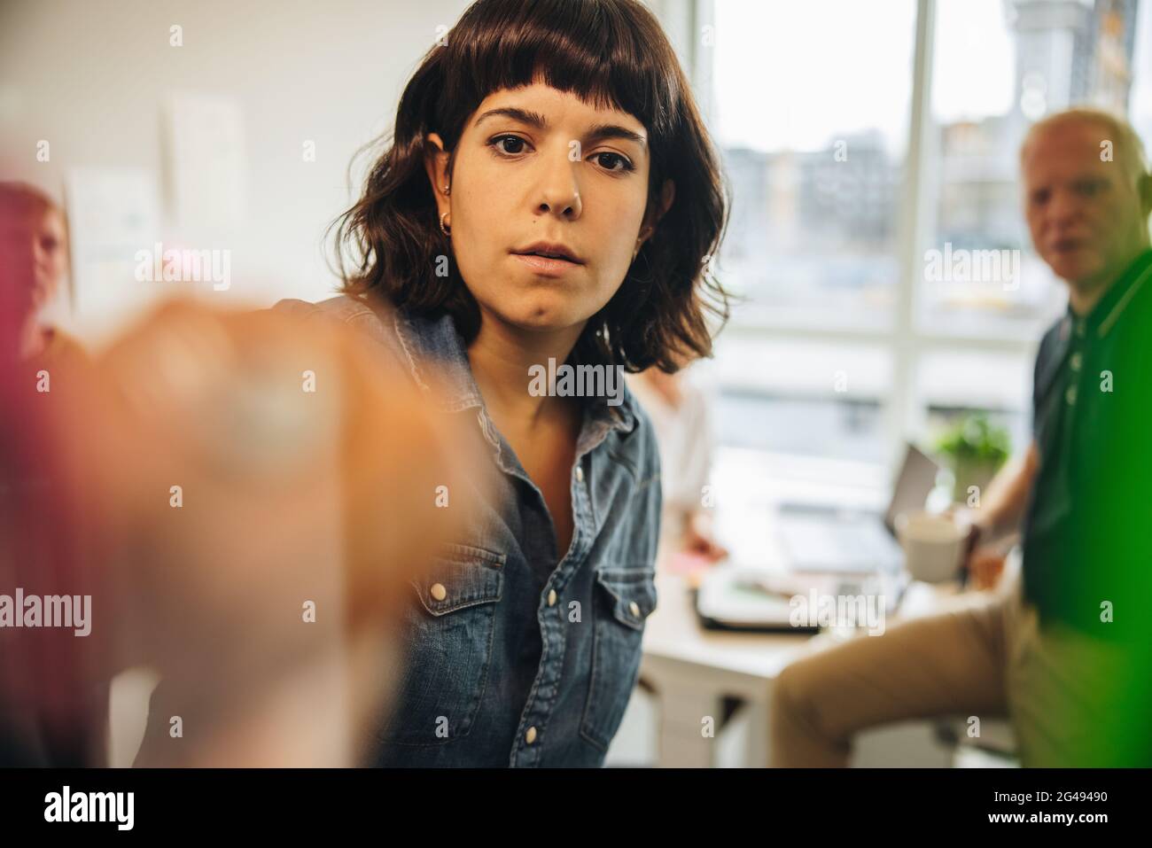 Young woman brainstorming using adhesive notes on glass wall. Female ...