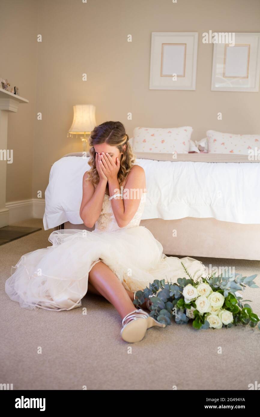 Bride in wedding dress crying while sitting by bed Stock Photo - Alamy