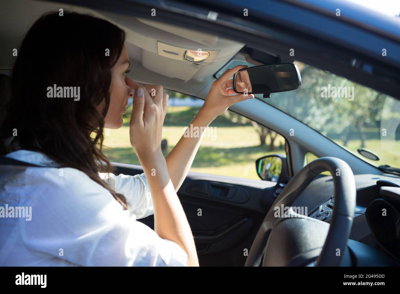 Woman looking into rear view mirror while driving a car Stock Photo - Alamy