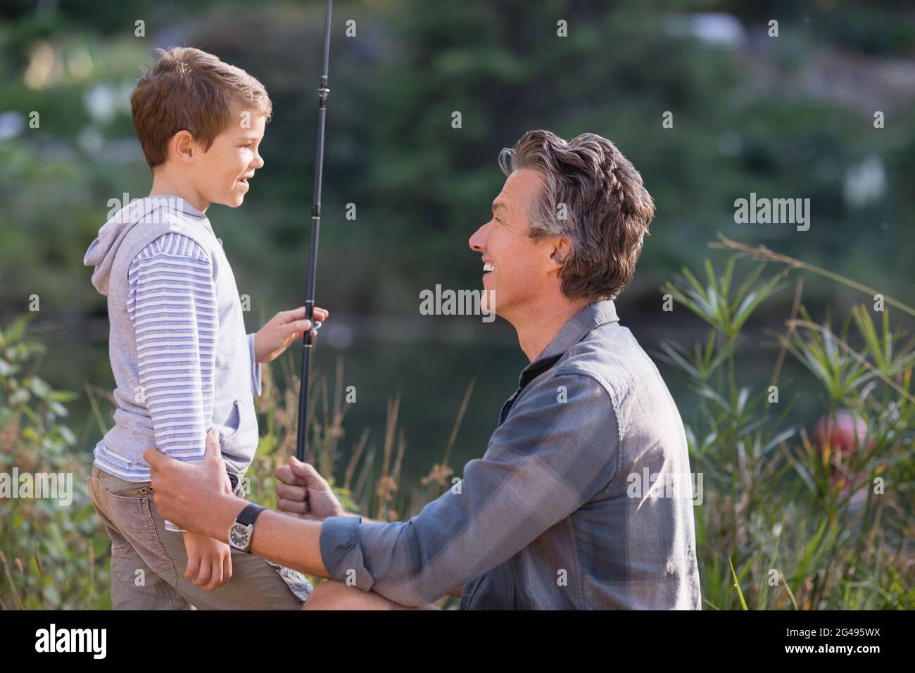 Smiling father and son holding fishing rod Stock Photo - Alamy