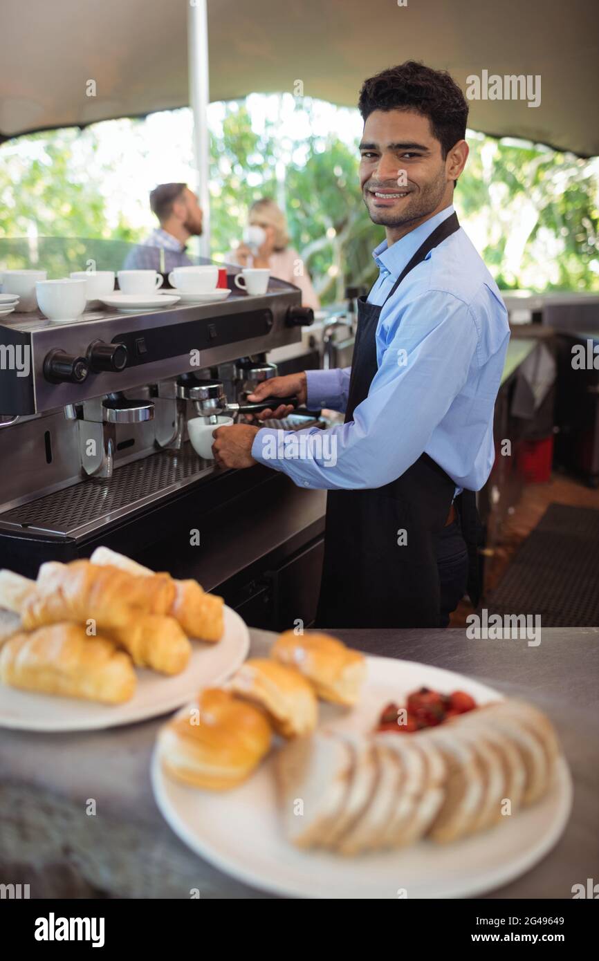 Smiling waiter making cup of coffee from espresso machine Stock Photo ...
