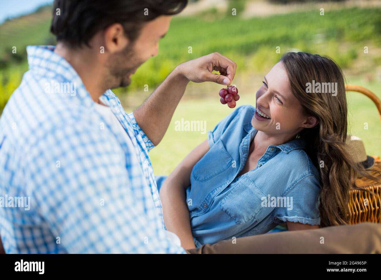 Man feeding grapes to cheerful partner Stock Photo - Alamy