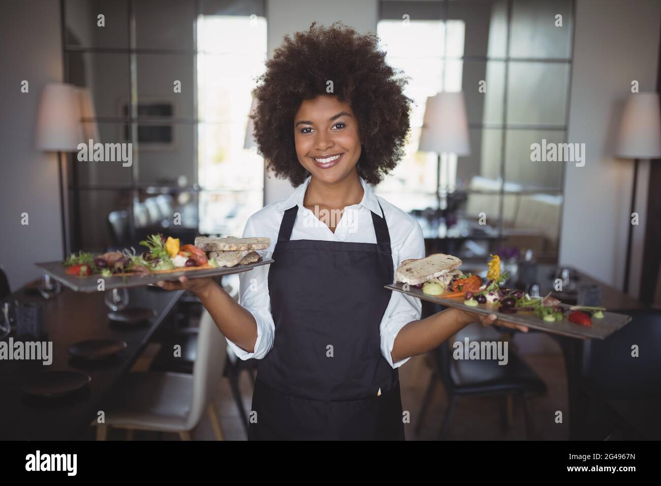 Portrait of smiling waitress holding food tray Stock Photo - Alamy
