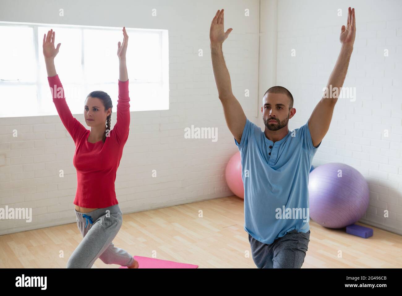 Instructor with student practicing warrior 1 pose in yoga studio Stock ...