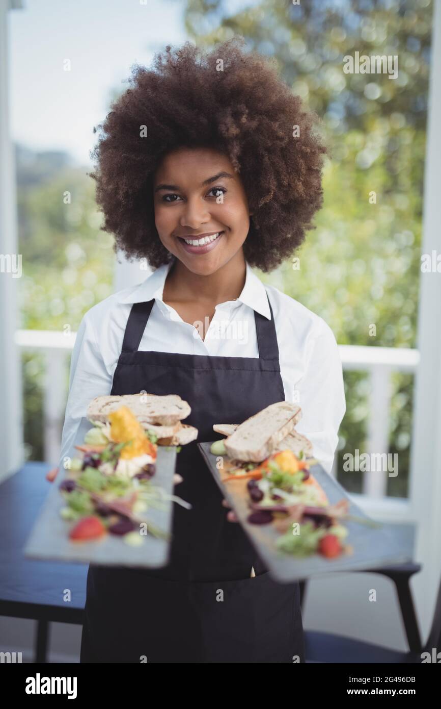Portrait of smiling waitress holding food tray Stock Photo - Alamy