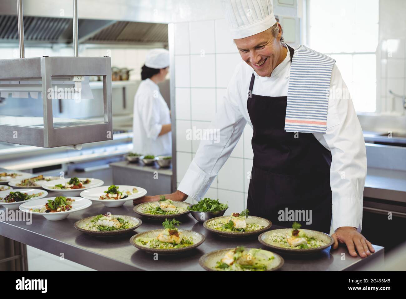 Happy chef examining appetizer plates at order station Stock Photo - Alamy