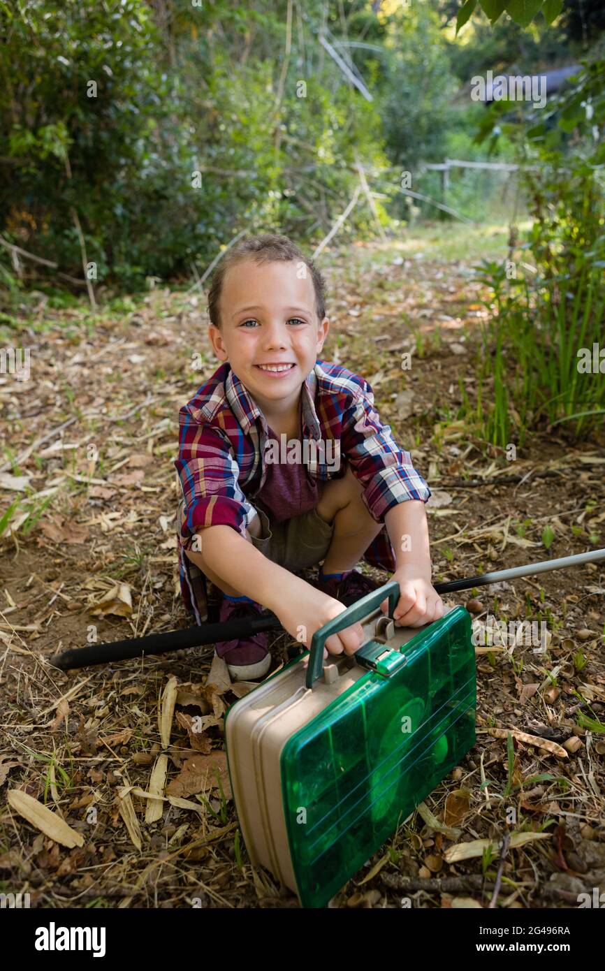 Smiling boy with fishing rod opening a box Stock Photo - Alamy