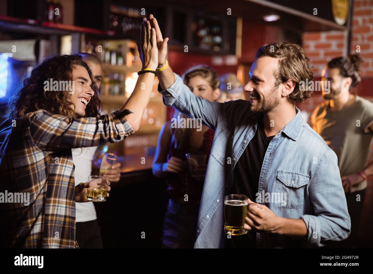 Friends doing high five in club Stock Photo - Alamy