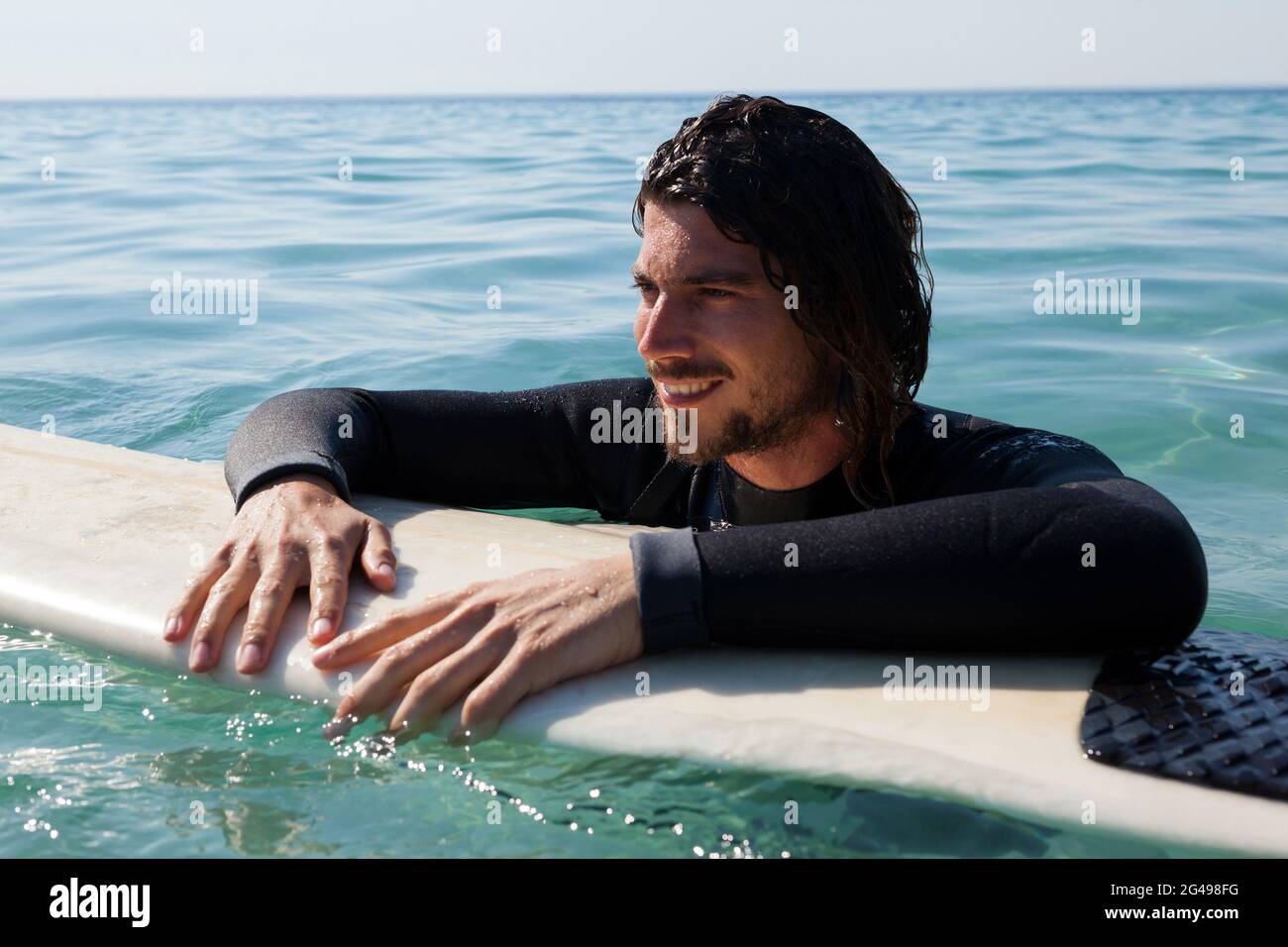 Surfer leaning on surfboard in sea Stock Photo - Alamy