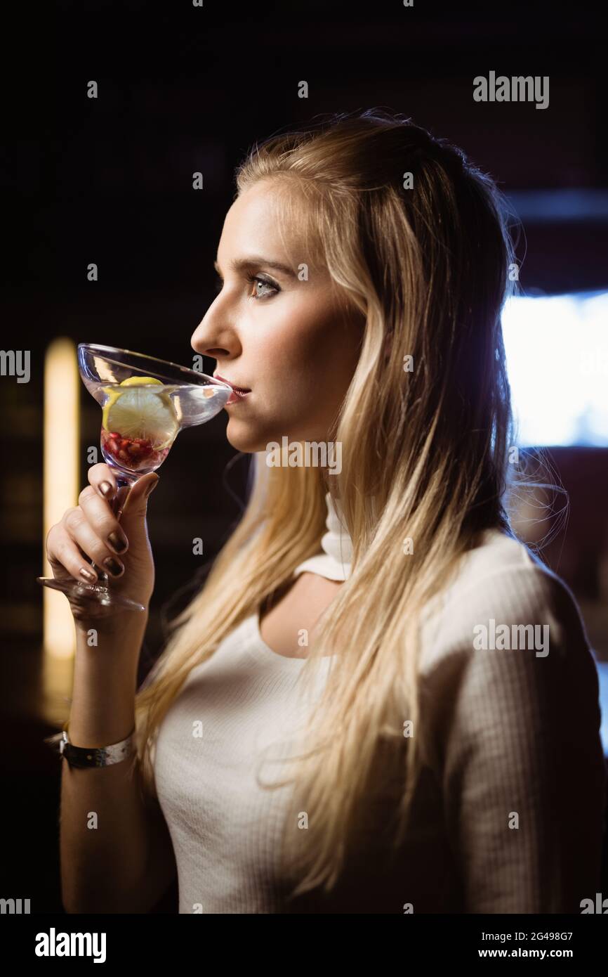 Side view of thoughtful woman drinking martini Stock Photo - Alamy