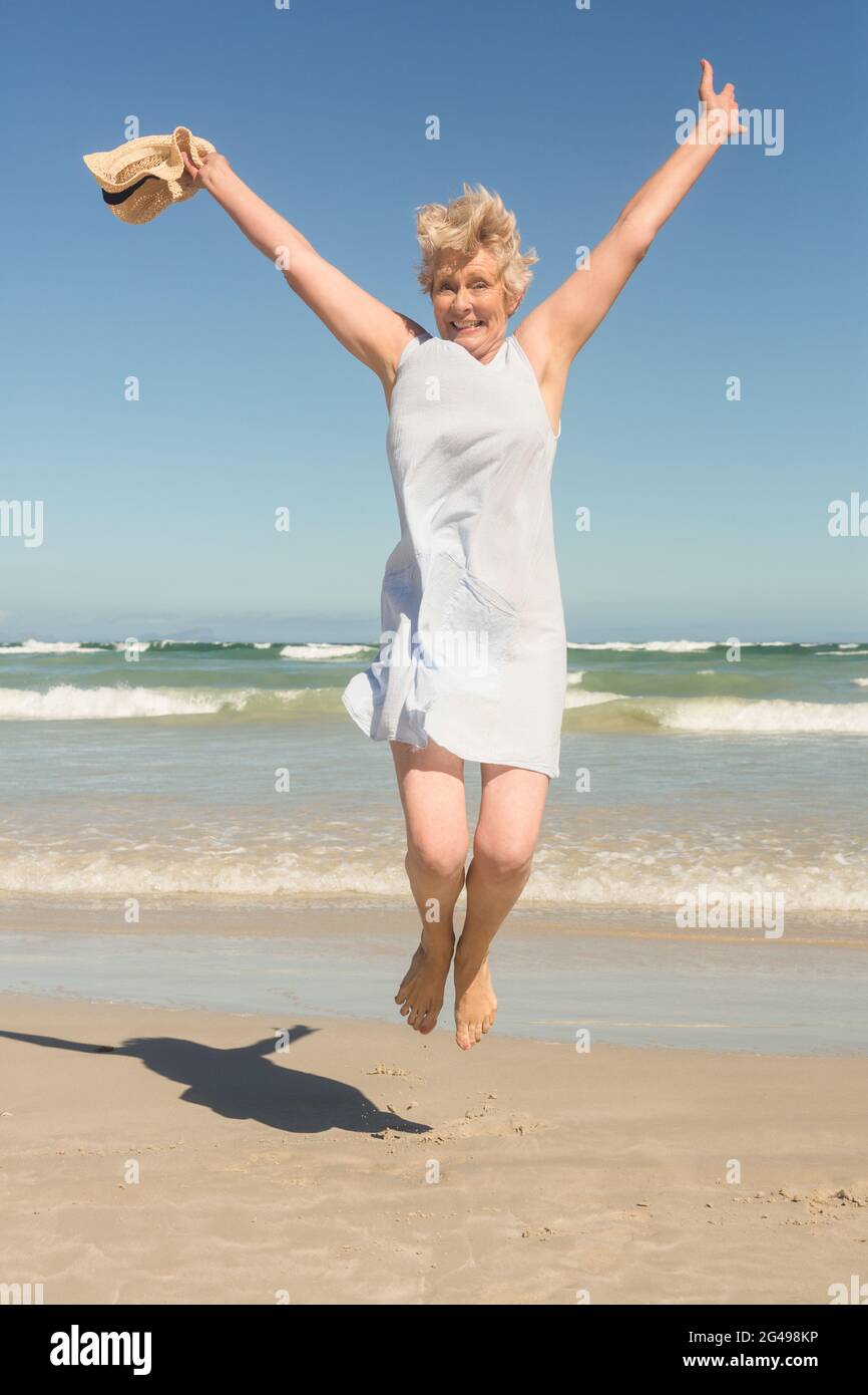 Portrait of happy senior woman jumping on sand against clear sky Stock ...