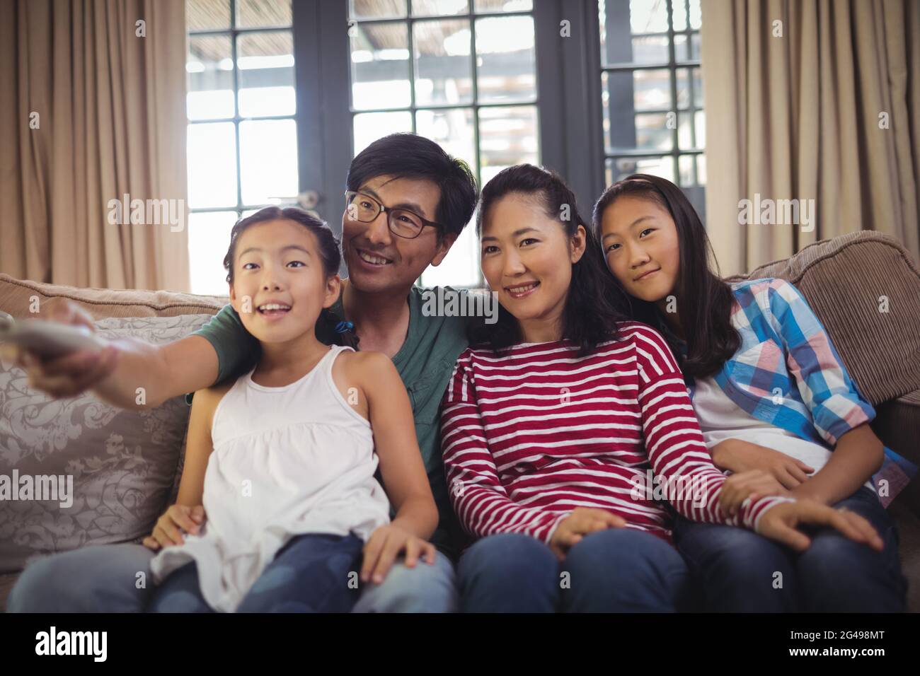 Smiling family watching television together in living room Stock Photo ...