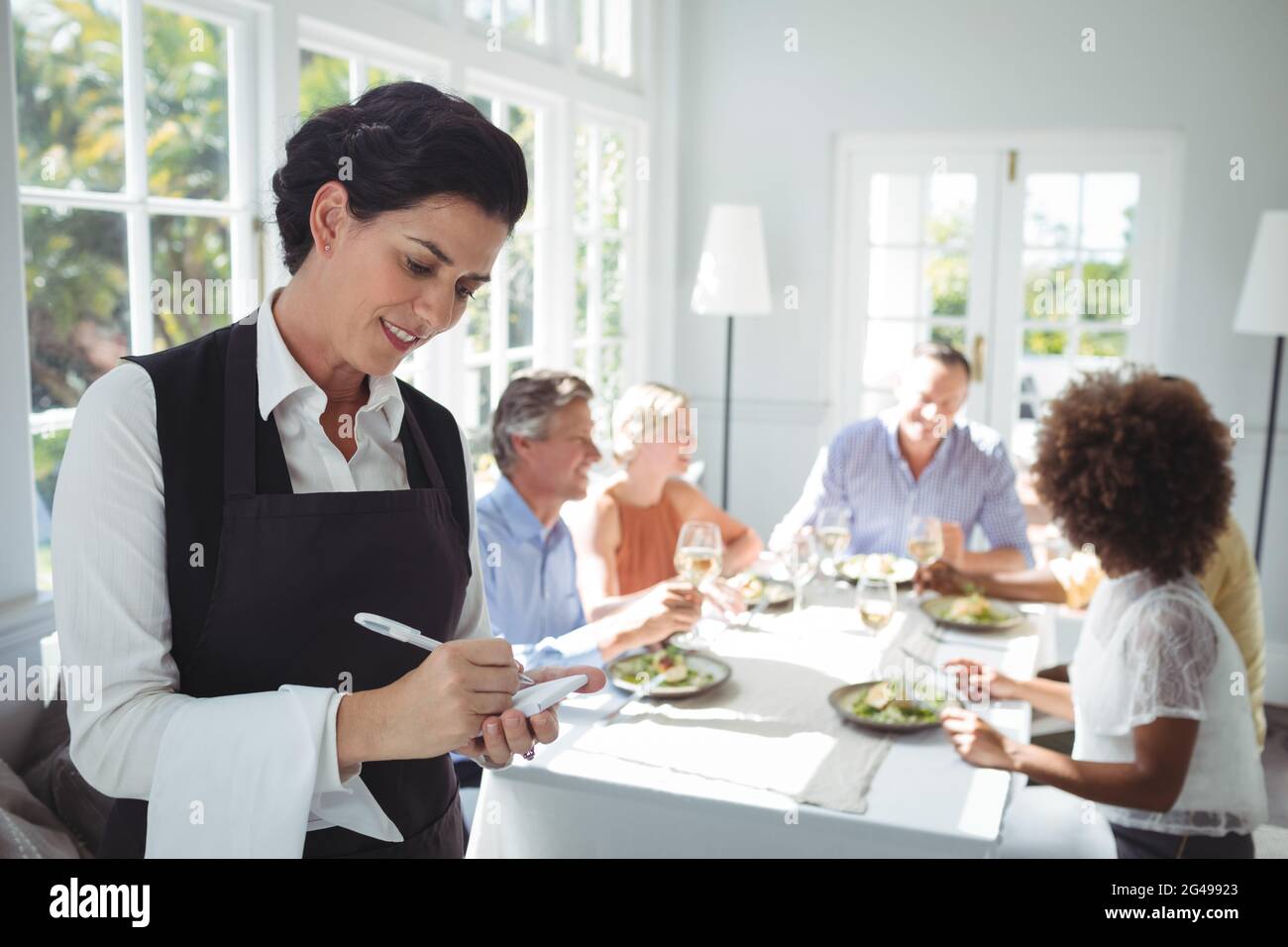 Smiling waitress writing order in notepad Stock Photo - Alamy