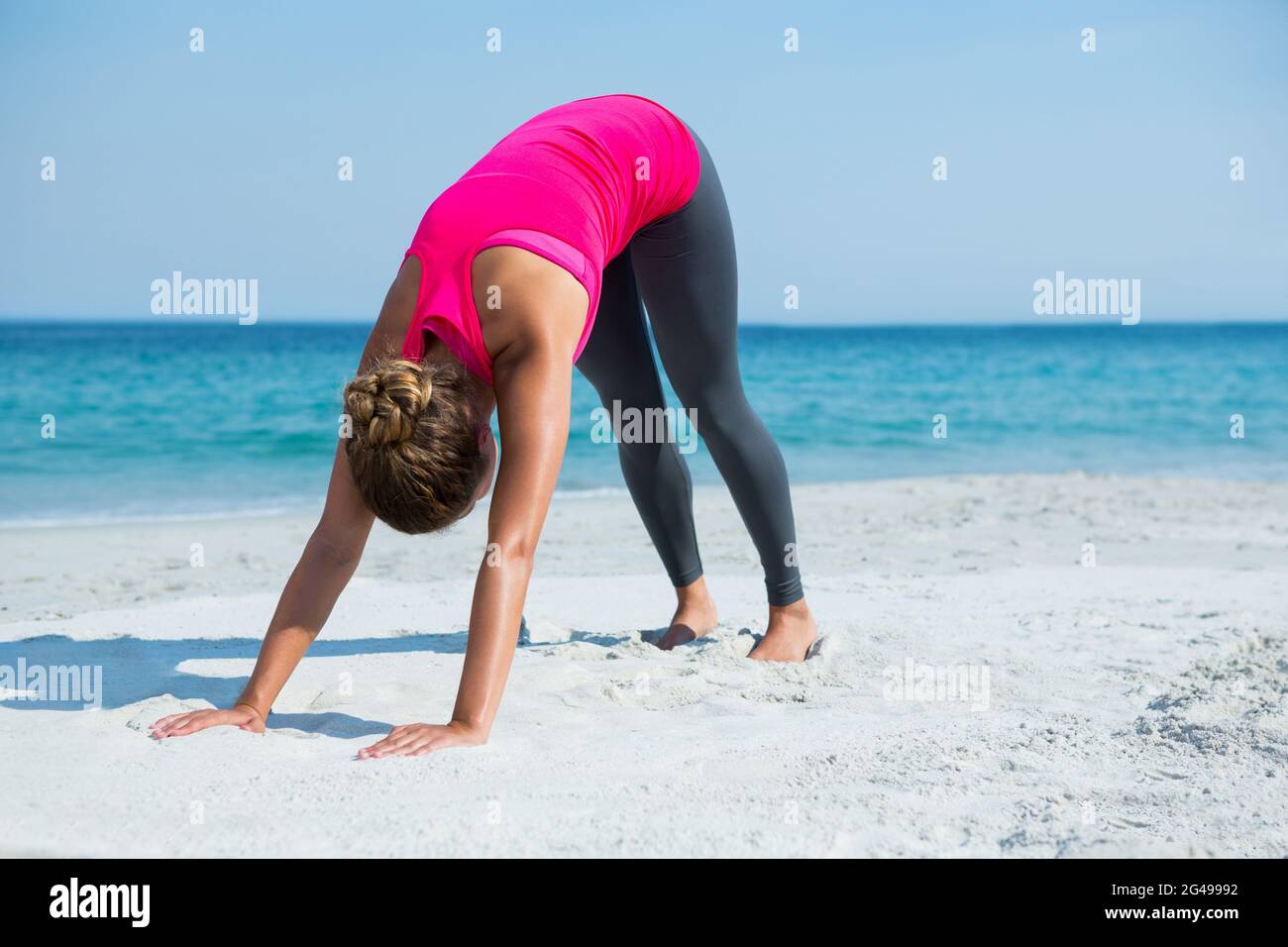 Woman bending on sand while exercising at beach Stock Photo - Alamy